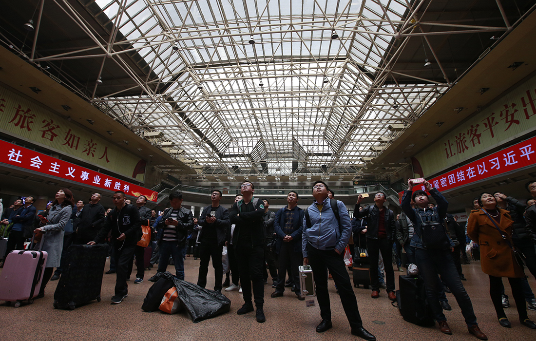 Travelers watch large screen broadcast of Party's newly-elected central ...