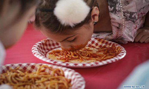 Girls participate in spaghetti eating contest during Italian Day ...
