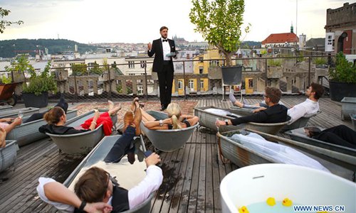 Audience watch performance in hot tubs on roof of building in Prague ...