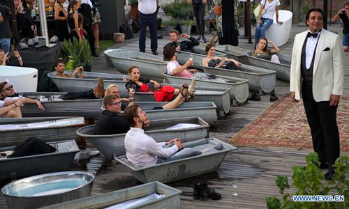 Audience watch performance in hot tubs on roof of building in Prague ...