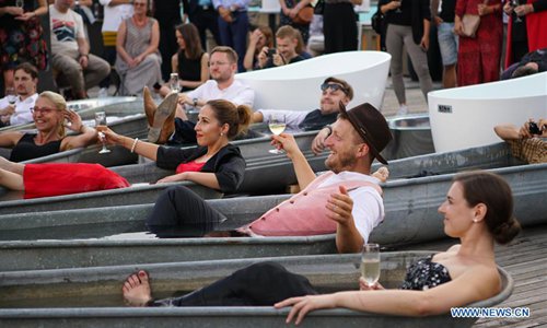 Audience watch performance in hot tubs on roof of building in Prague ...