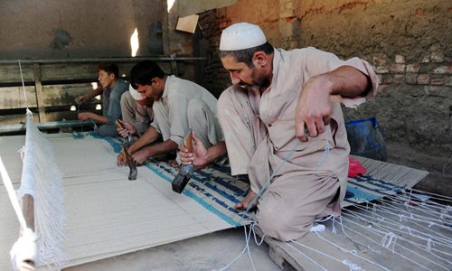 Pakistani workers make carpet at carpet factory in Peshawar - Global Times
