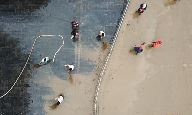 Workers clean up mud-covered roads after flood recedes in Jishou City ...