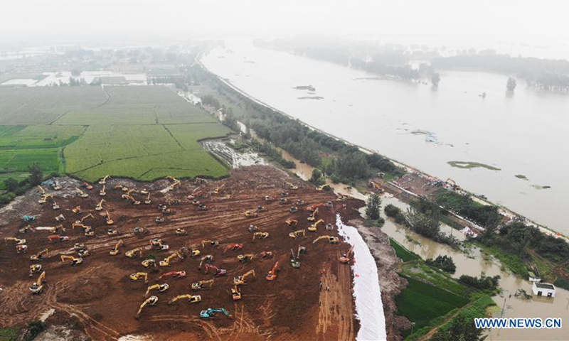 Heavy machineries work to build temporary embankment to prevent ...