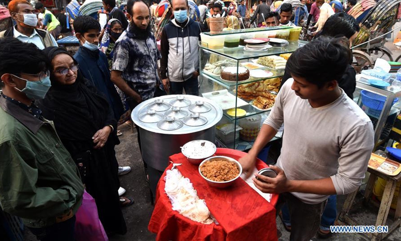 People gather at roadside stall to eat winter cakes in Dhaka ...