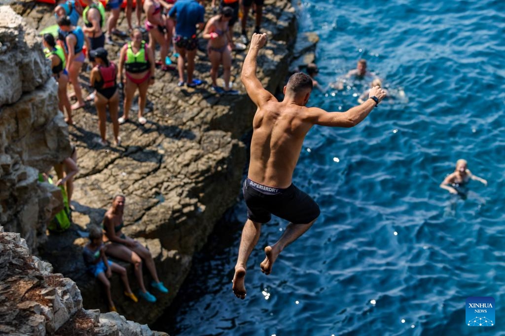 People dive into sea to cool off at Seagull's Rocks Beach in Croatia ...
