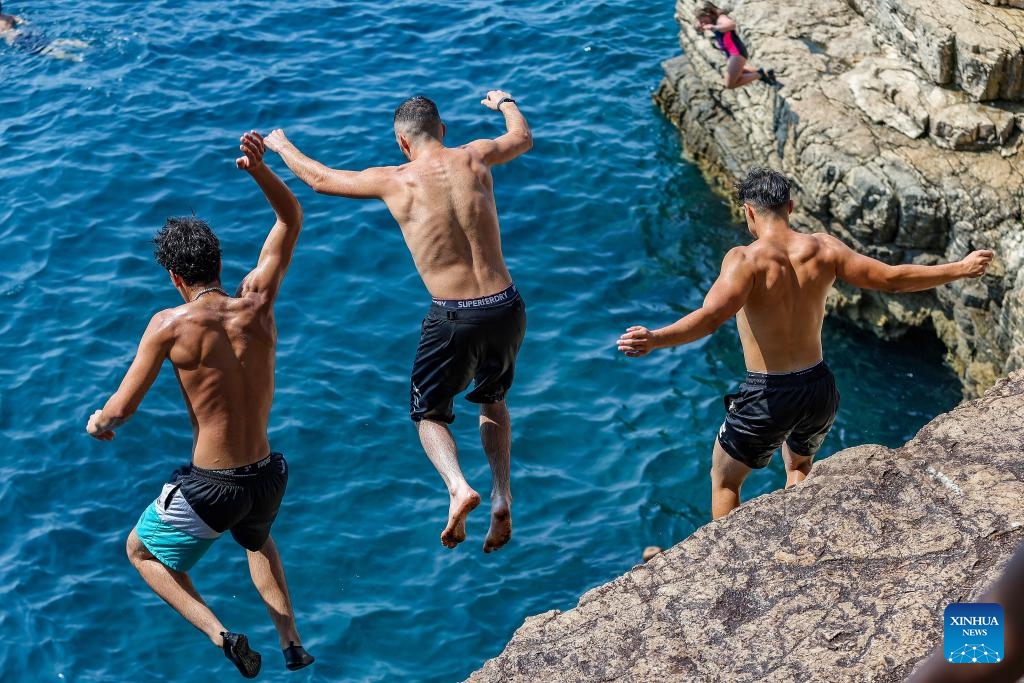 People dive into sea to cool off at Seagull's Rocks Beach in Croatia ...