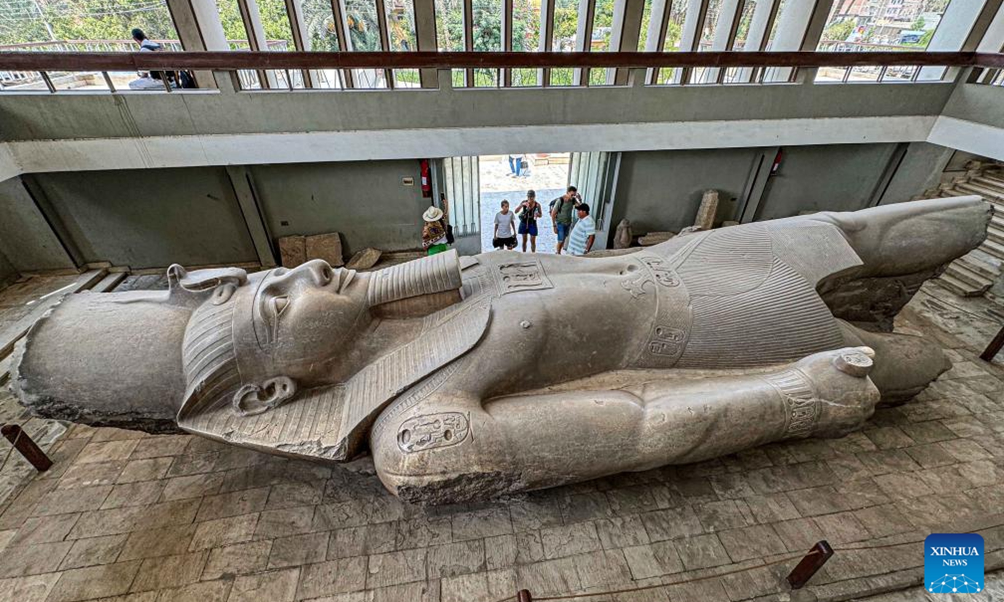 Tourists look at statue of ancient Egyptian king at Mit Rahina Museum ...
